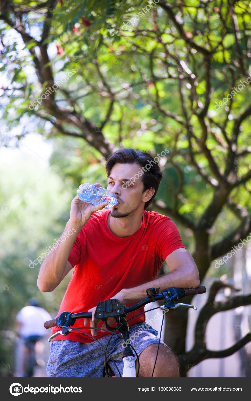 Young man sit on bike in wood resting drink water Stock Photo by ...