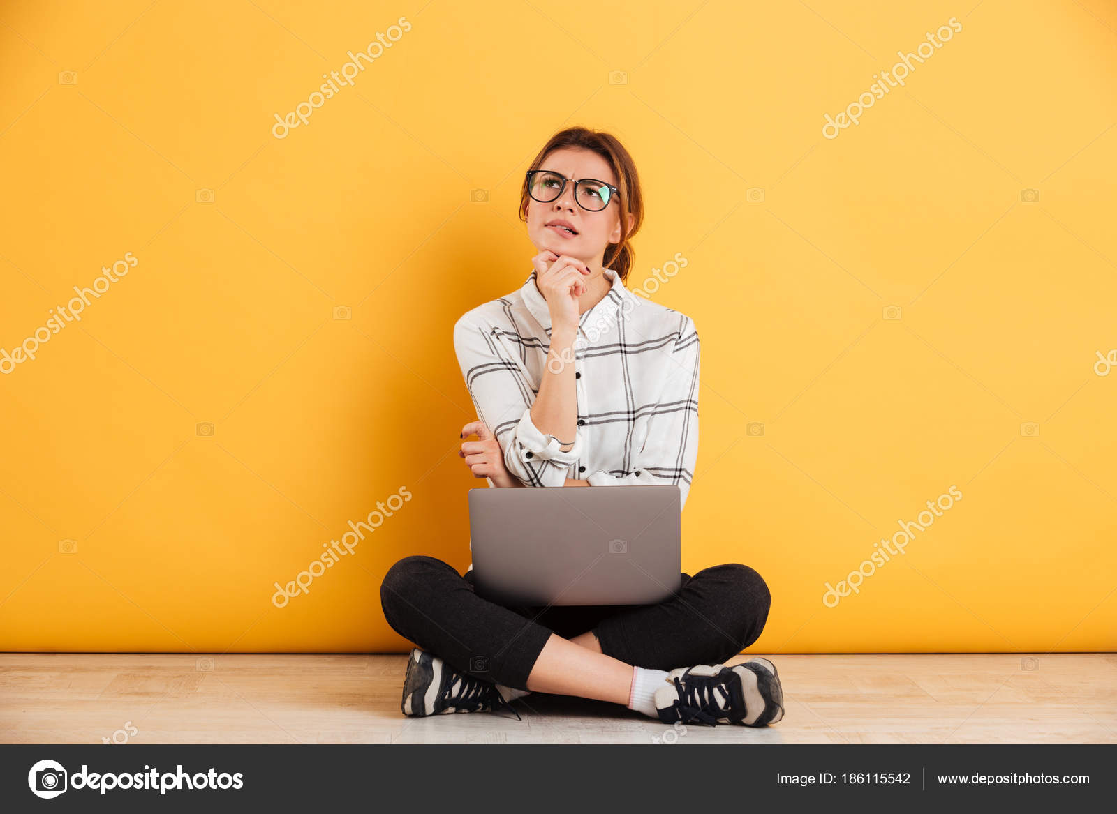 Thoughtful woman touching her chin and looking upward while sitt Stock ...