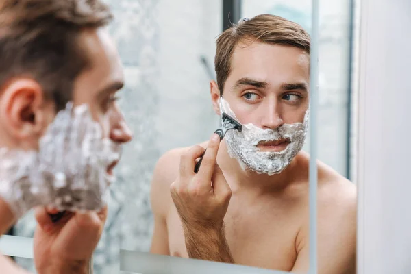 Attractive young shirtless man shaving - Stock Image - Everypixel