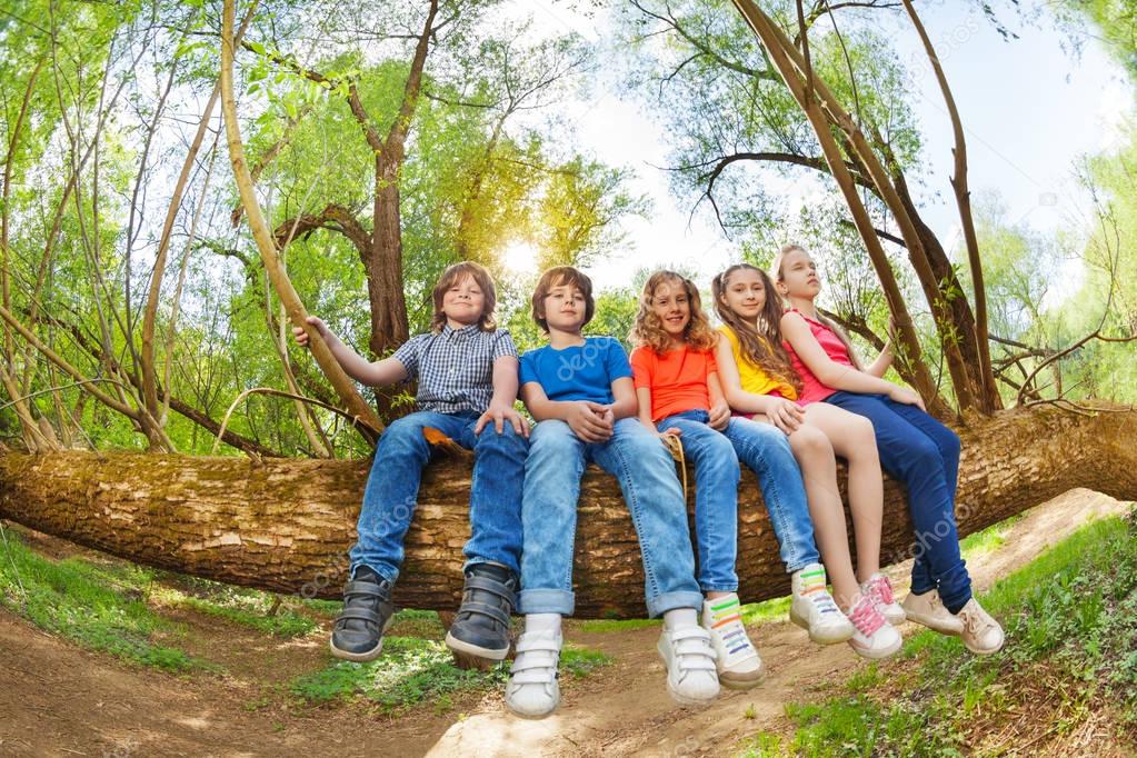 Kids sitting on fallen tree Stock Photo by ©serrnovik 130011310