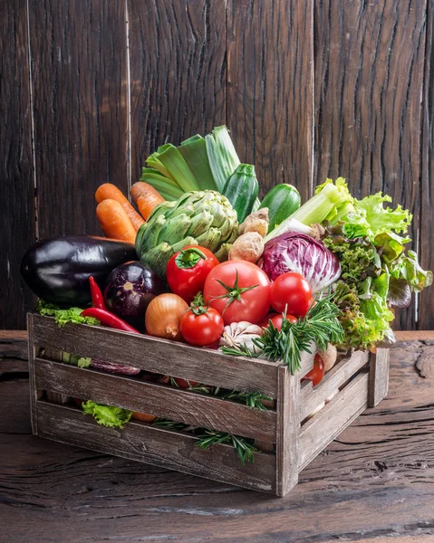 Fresh multi-colored vegetables in wooden crate. Wooden backgroun ...