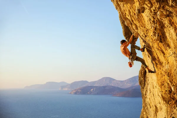Young man trying to reach cliff in order to continue climbing - Stock ...