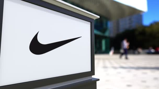 Street signage board with Nike logo. Blurred office center and walking ...