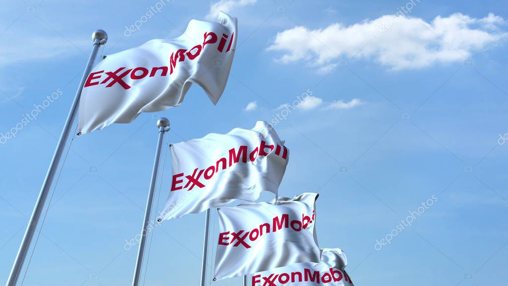 ondeando banderas con el logotipo de Exxon Mobil contra el cielo ...