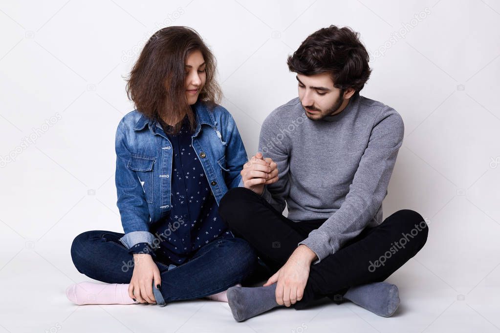A Happy Couple Sitting On The Floor Crossed Legs Holding Each Other`s
