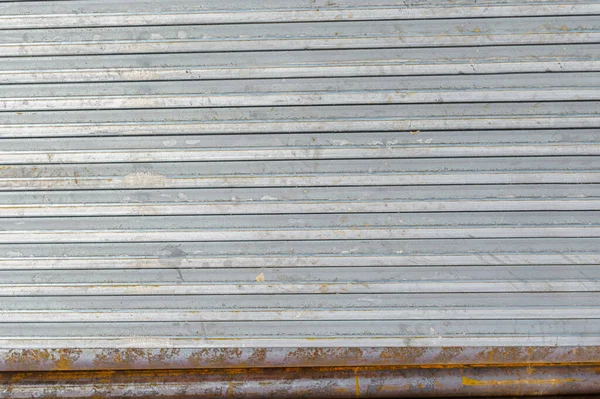 Racks of metal profiles. Metal is stored in an open warehouse. Wet and ...