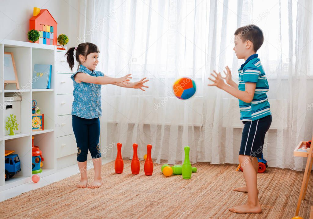 niño nativo y una niña juegan en una sala de juegos para niños, lanzando pelota. concepto de ...