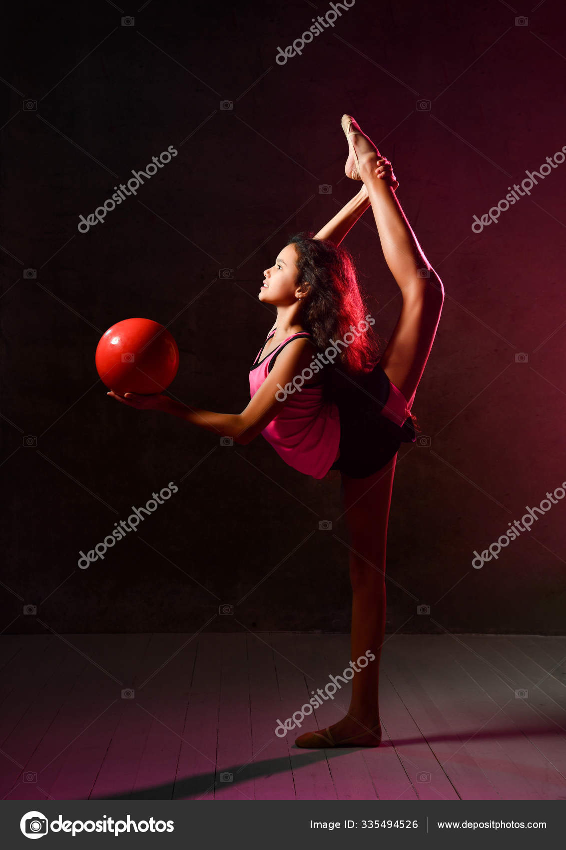Young athletic girl gymnast doing gymnastic exercises with red ball and ...