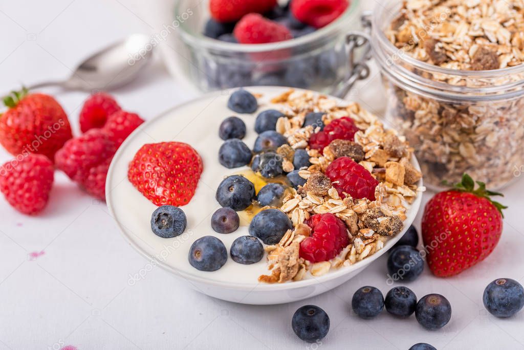 Yogur en tazón blanco con fresas y arándanos sobre fondo blanco.Yogur ...