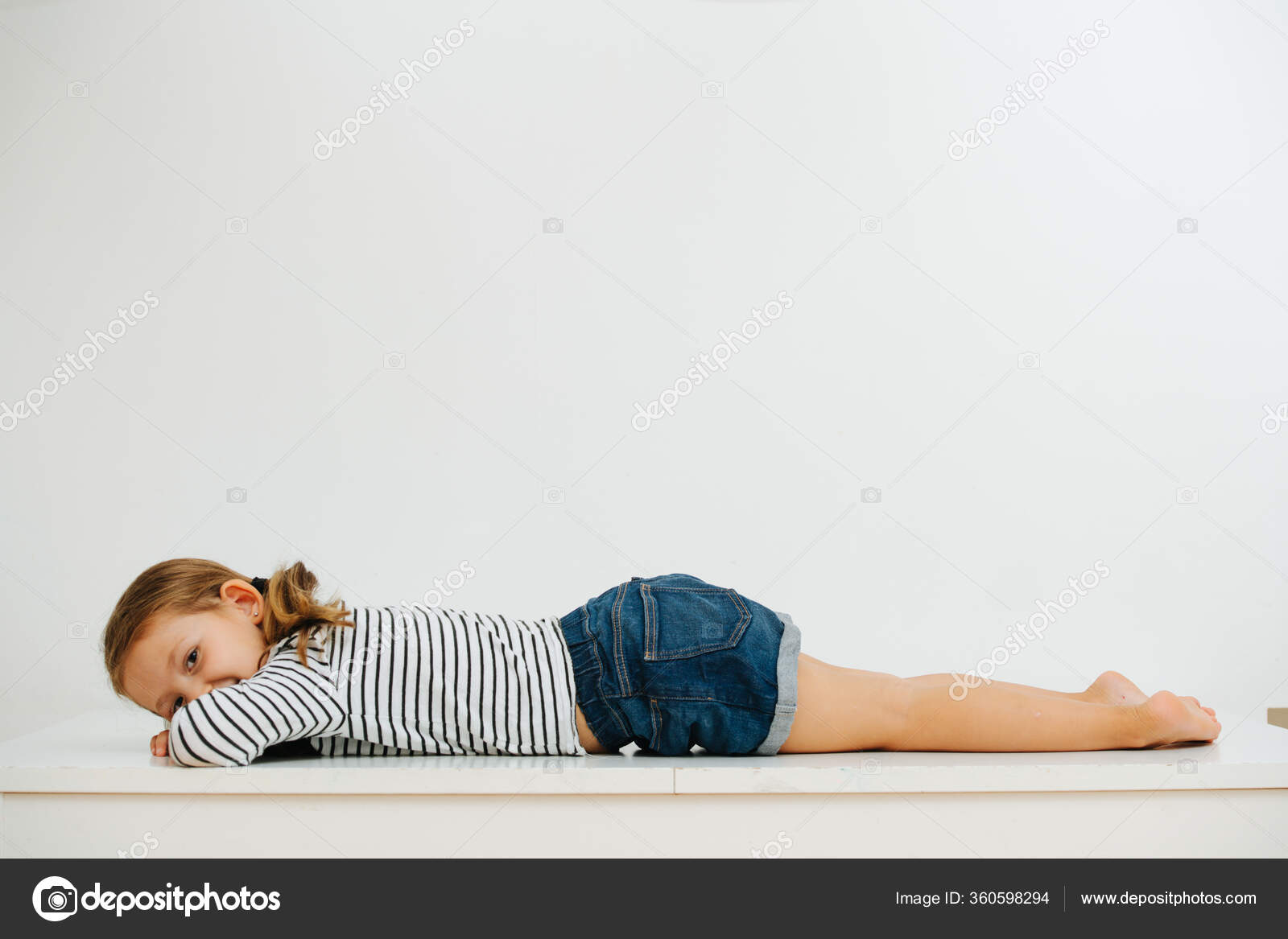 Happy Smiling Little Barefoot Girl Lying Table White Wall Wearing Stock Photo by ©zzzdim 360598294