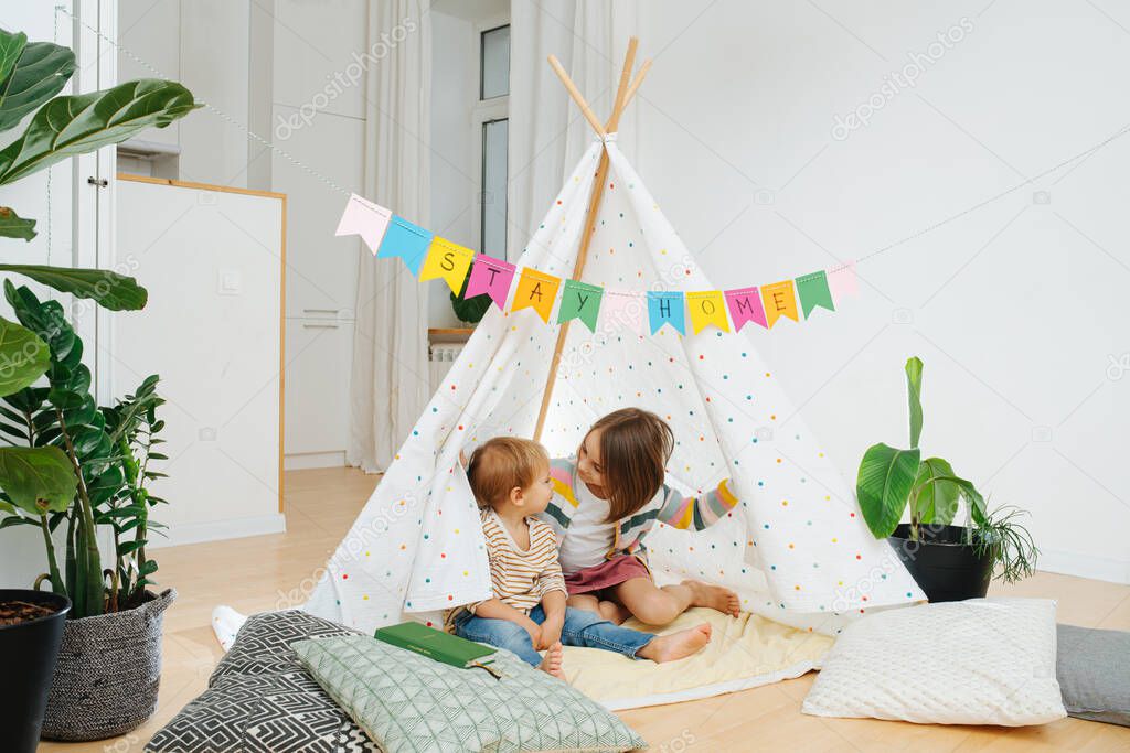 Hermanitos sentados en una manta en una choza, hechos con palos y ...