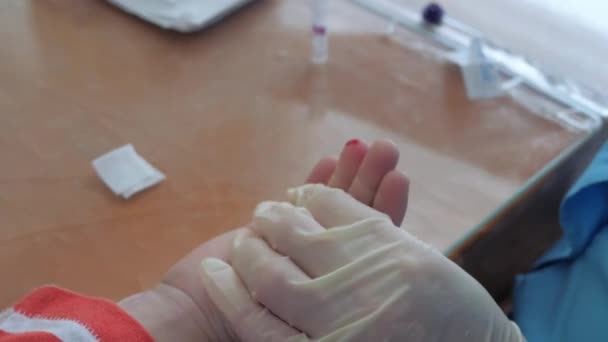 Nurse takes blood from a finger of child in medical laboratory. Blood ...