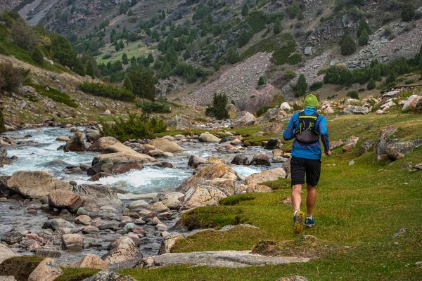 Runner guy is jogging in the highlands. Athlete runs near a mountain ...