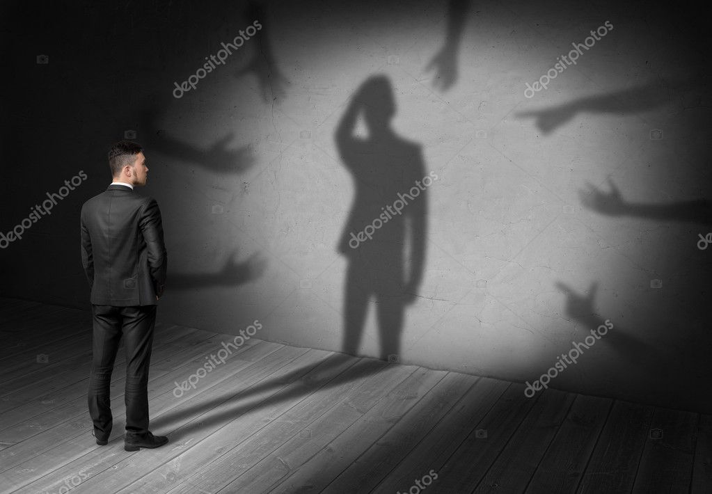 Businessman looking at shadow where many hands reach for him forcing ...