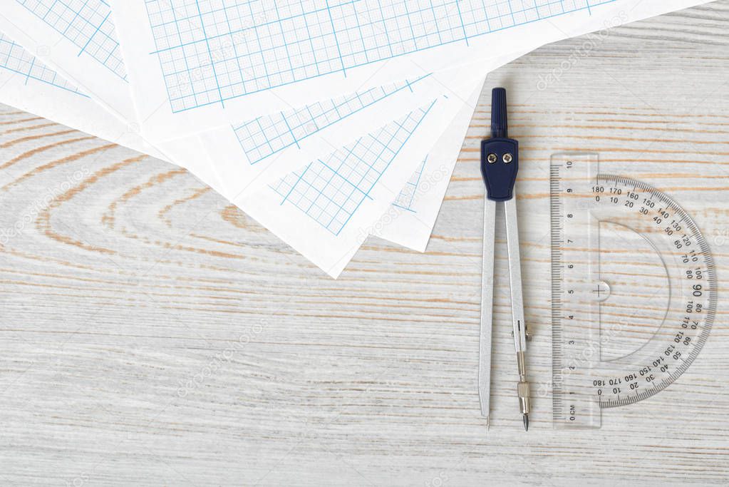 Layout with compass, protractor and graph paper on wooden surface in ...