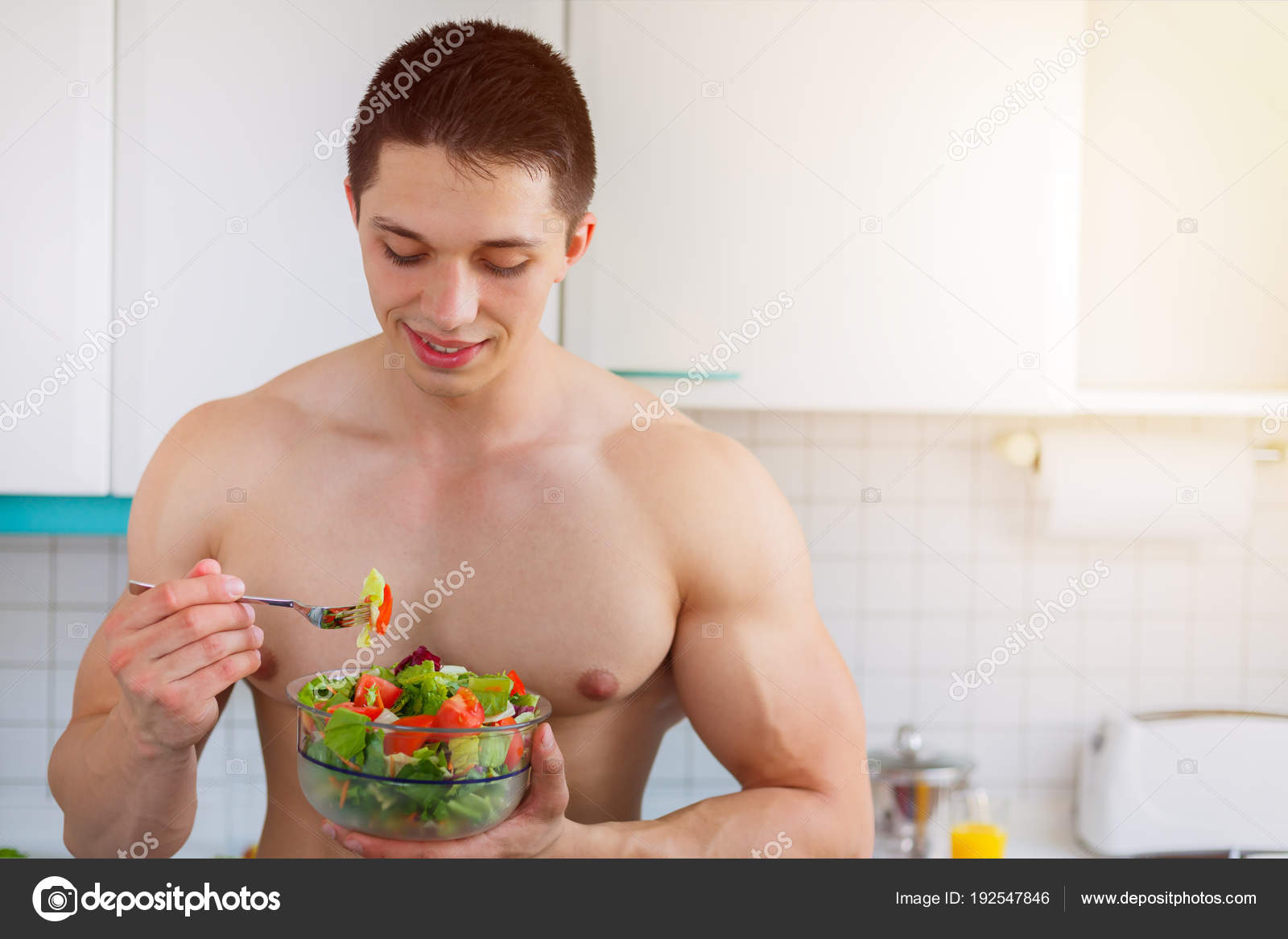 Bodybuilder young man eating salad in the kitchen copyspace heal Stock ...