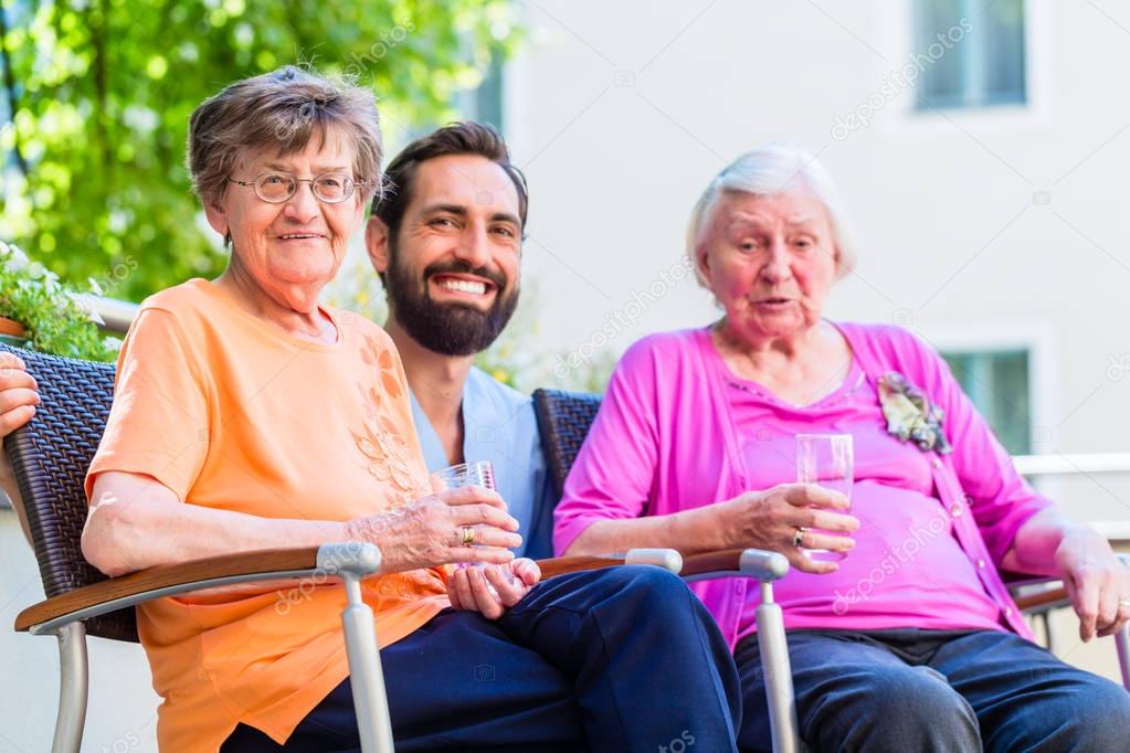 Enfermera bebiendo café con personas mayores en la terraza del asilo 2024