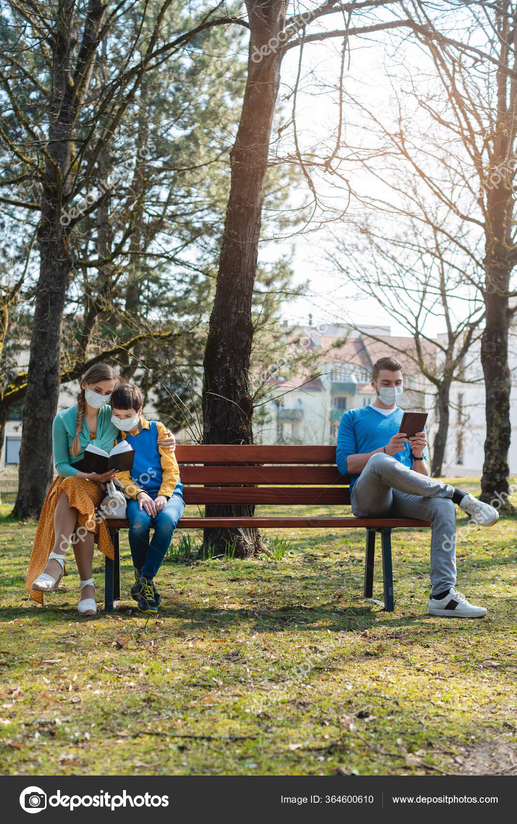 People sitting on park bench in the sun practicing social distancing ...