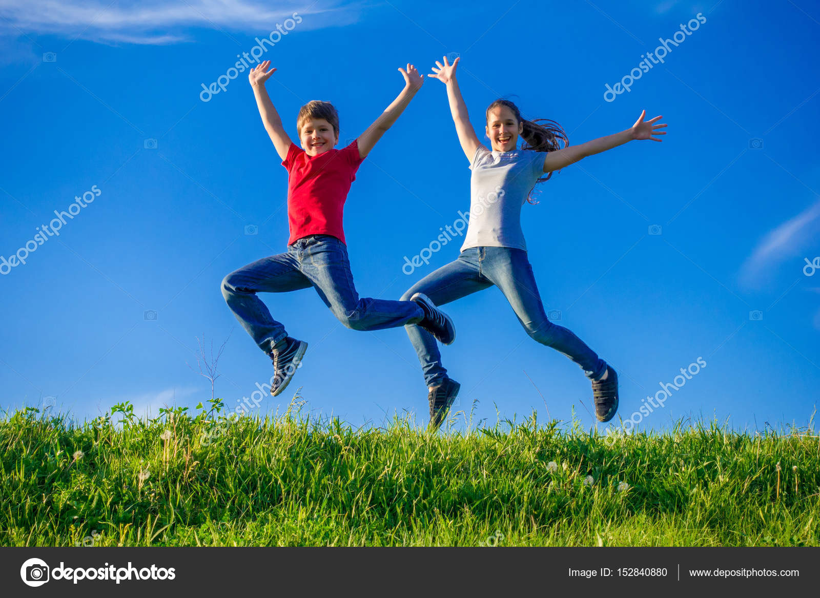 Two kids jumping together on green spring hills — Stock Photo ...