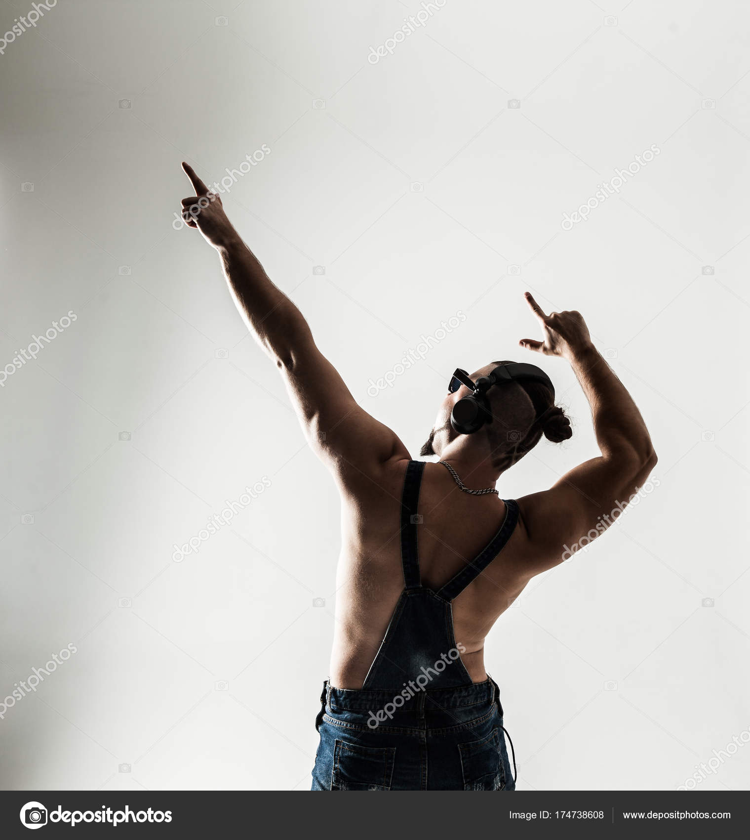 Rear view - the rapper shirtless with headphones and stylish hai ...