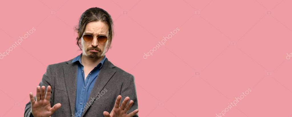 Joven guapo molesto con mala actitud haciendo señal de stop con la mano ...