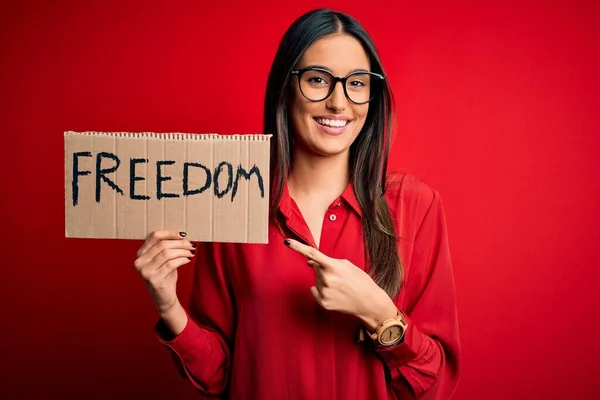 Young beautiful brunette activist woman wearing glasses protesting for ...