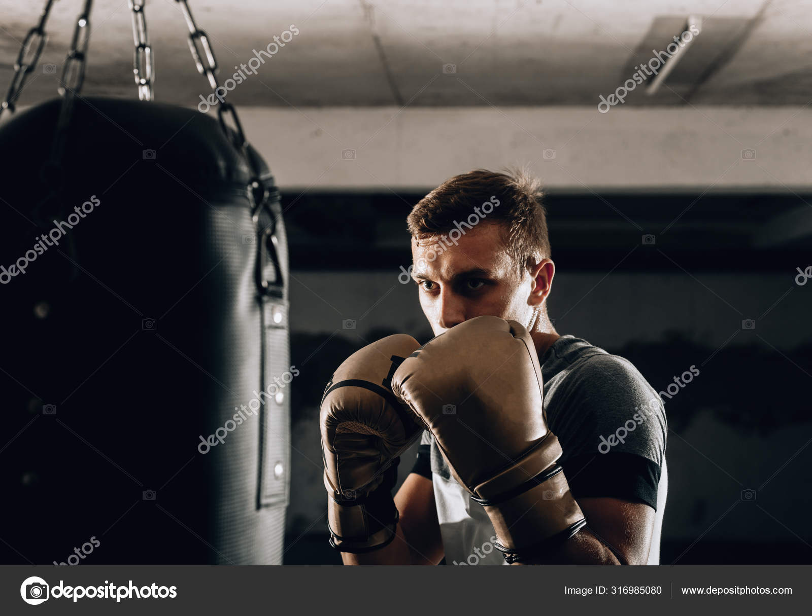 Aggressive boxer in boxing gloves training with punching bag Stock ...