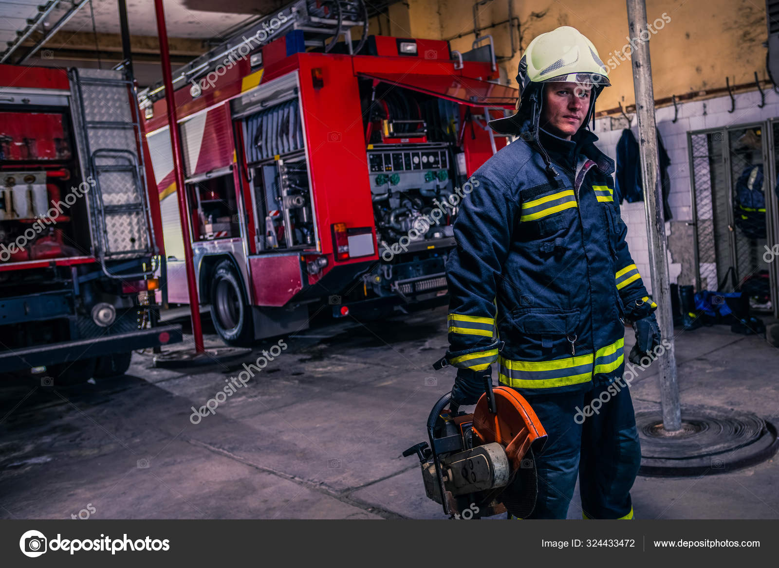 A fireman with uniform and helmet holding a chainsaw with fire t ...