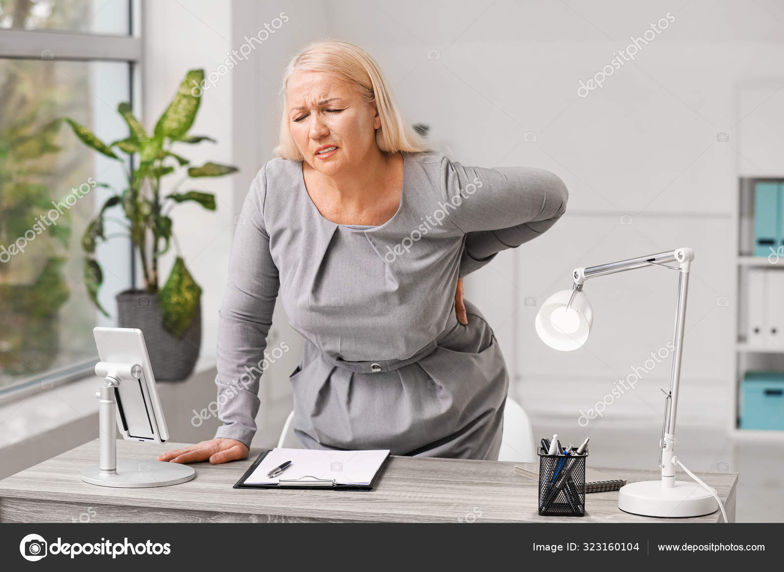 Mature woman suffering from back pain in office — Stock Photo ...