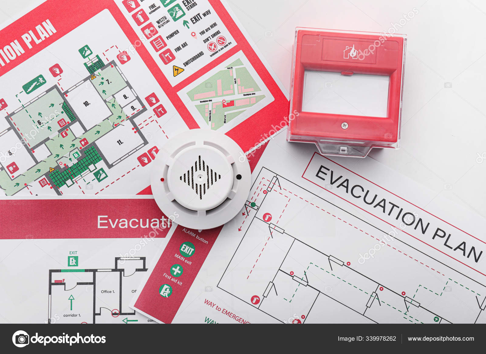 Evacuation plans, smoke detector and manual call point on white ...
