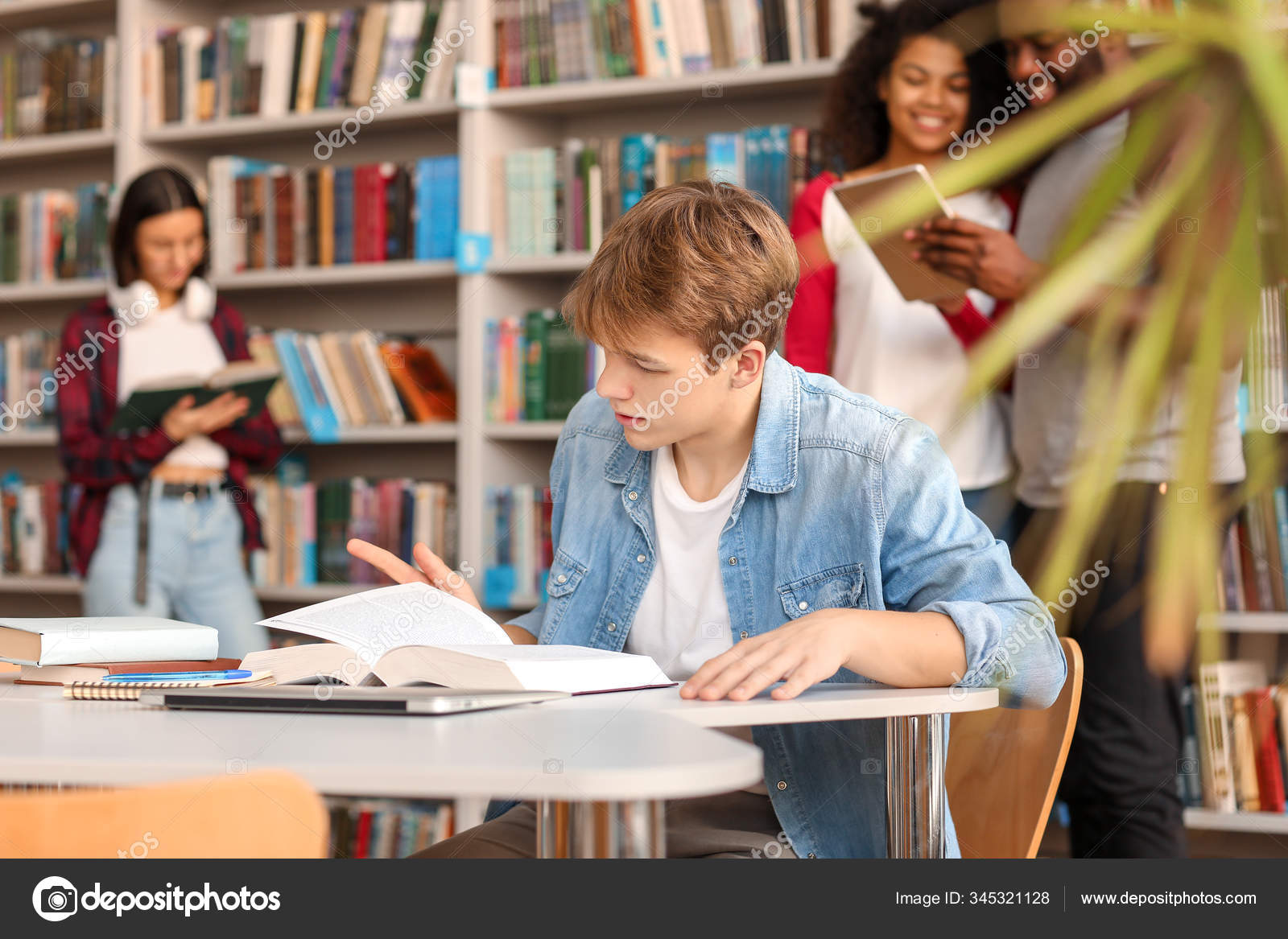 Male student reading book while preparing for exam in library — Stock ...