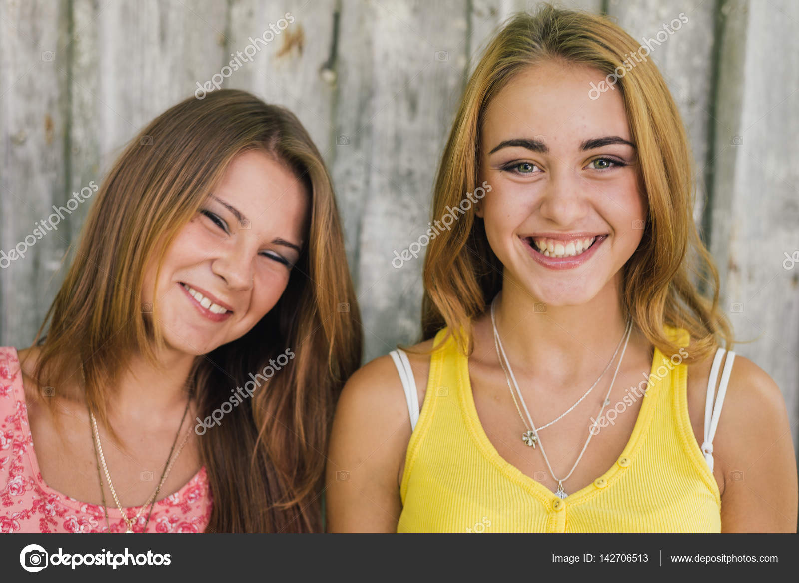 Two happy female friends smiling over pale wooden background — Stock ...
