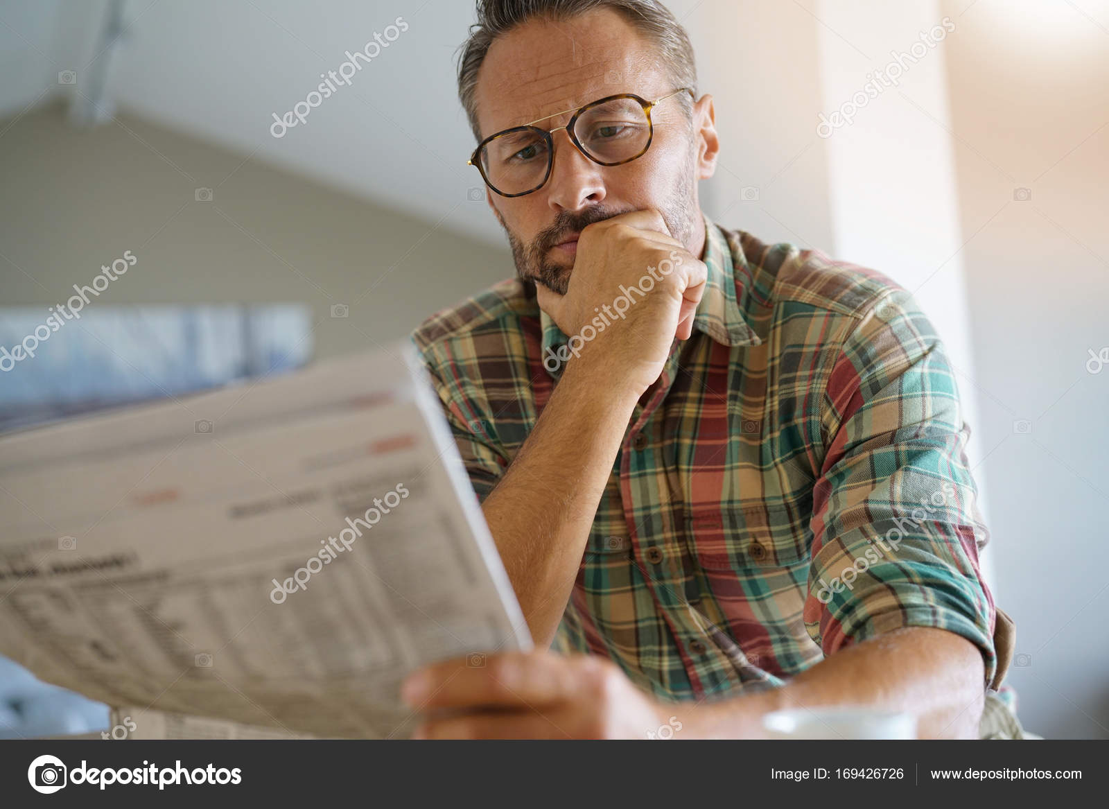 Man at home reading newspaper — Stock Photo © Goodluz #169426726