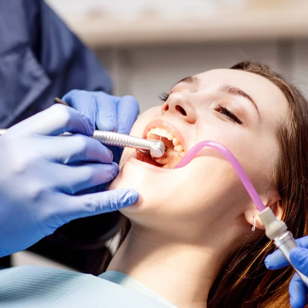 Dentist treating teeth to young woman patient in clinic. - Stock Image ...