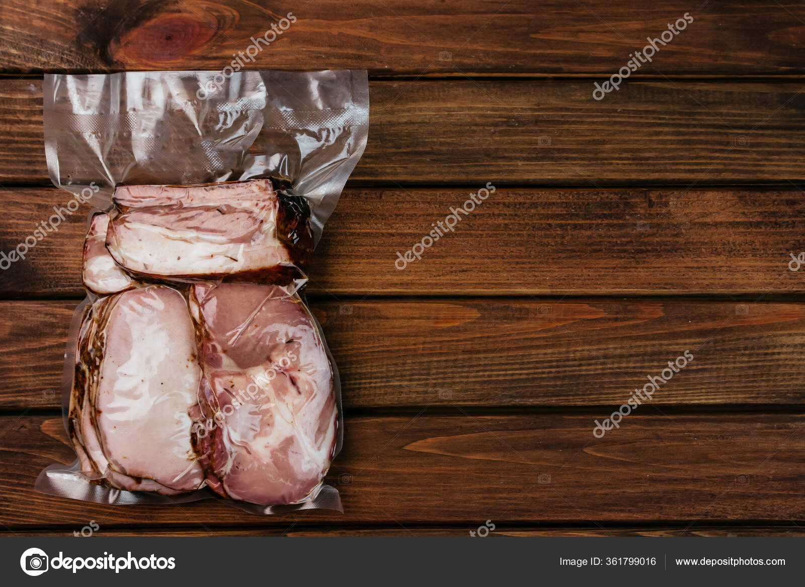 Smoked meat, sliced and packed in a vacuum package, closeup. Wooden ...