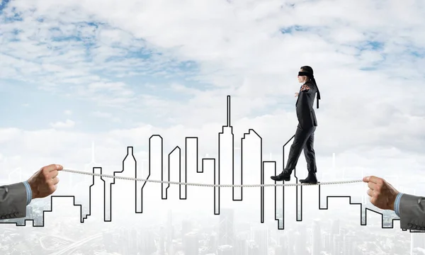 blindfolded businessman walking on rope over cityscape background ...