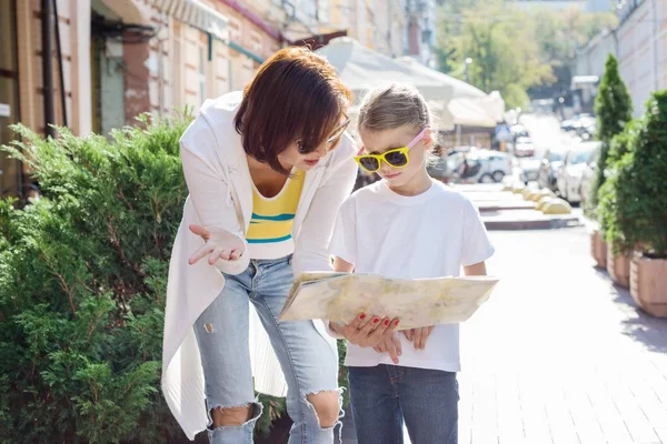 Back view of mom and daughter teen tourist looking at the map on Stock ...