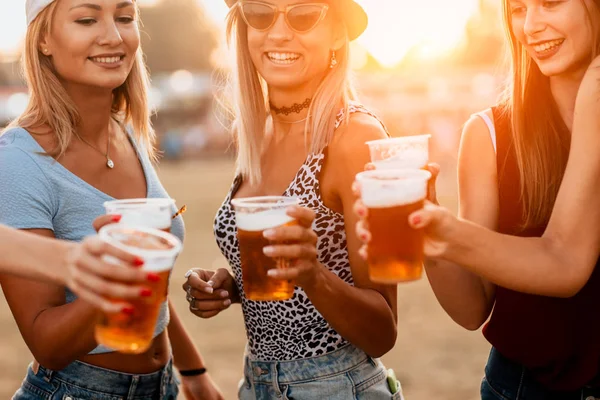 funny young women laughing and drinking beer on music festival weekends ...