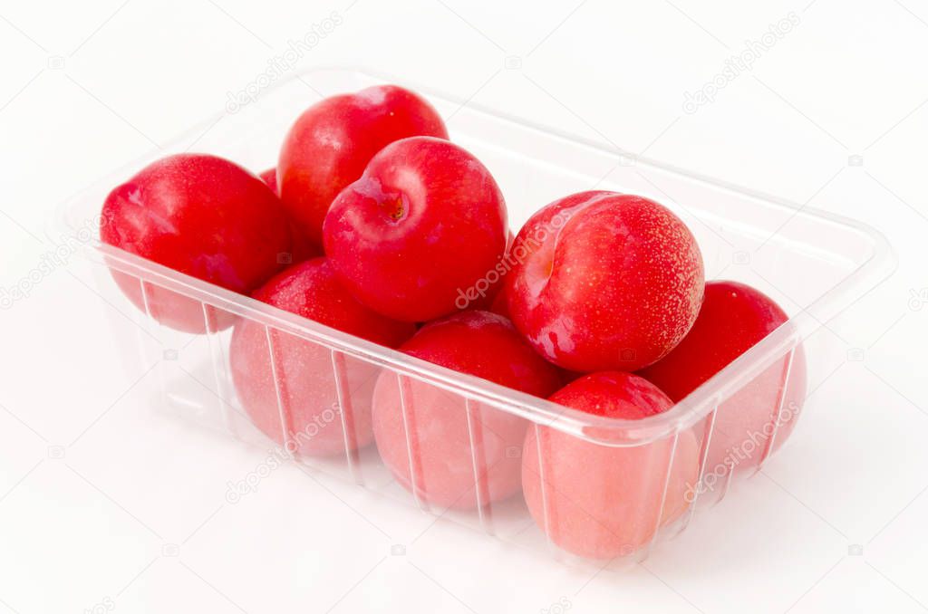 Punnet de ciruela japonesa fresca (Prunus salicina) sobre fondo blanco 2024