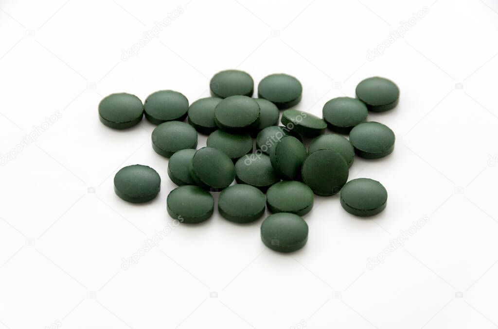 pastillas verdes, tabletas de espirulina sobre fondo blanco 2023