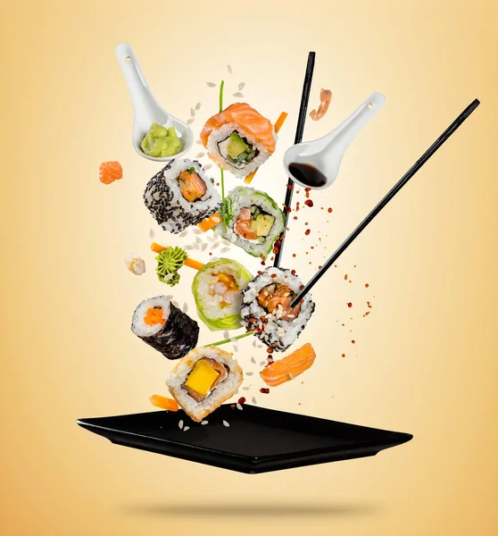 Flying sushi pieces served on plate, separated on colored backgr Stock ...
