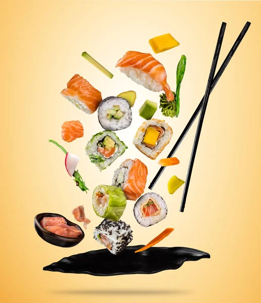 Flying sushi pieces served on plate, separated on colored backgr ...