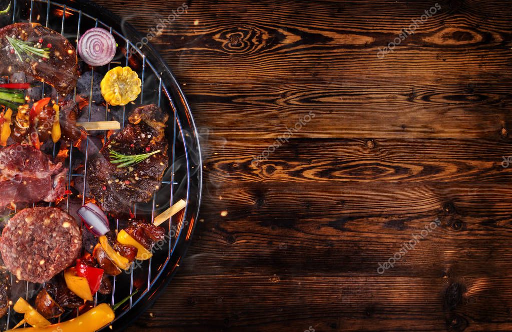Top view of fresh meat and vegetable on grill placed on wooden p ...