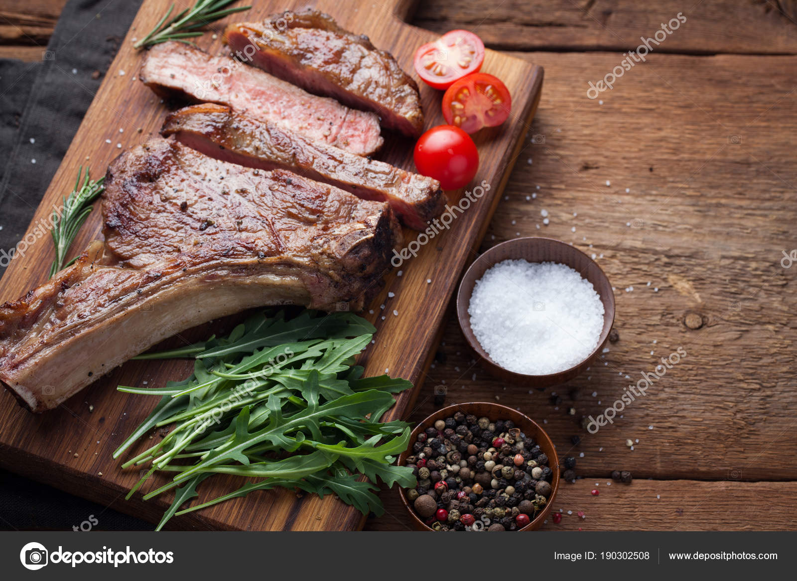 Grilled cowboy beef steak, herbs and spices on a rustic wooden ...