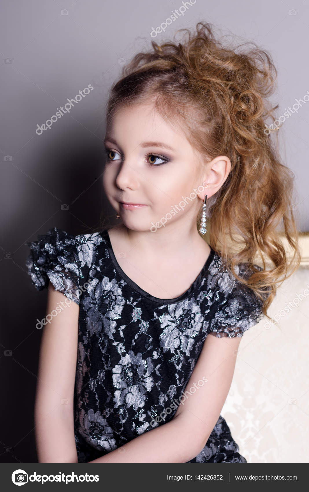 Small beautiful smiling baby in a smart dress jewelry shows on itself ...