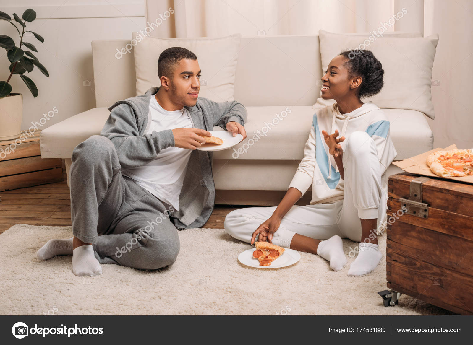 Couple eating pizza beside sofa — Stock Photo © NatashaFedorova #174531880