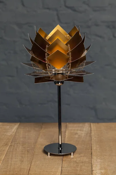 Front view of white conceptual table lamp on wooden stand on gray brick ...