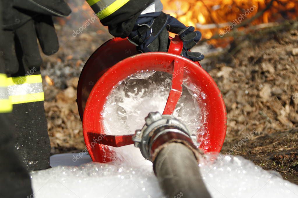 La mano del bombero sostiene una manguera de fuego para extinguir un fuego y apagar el fuego ...