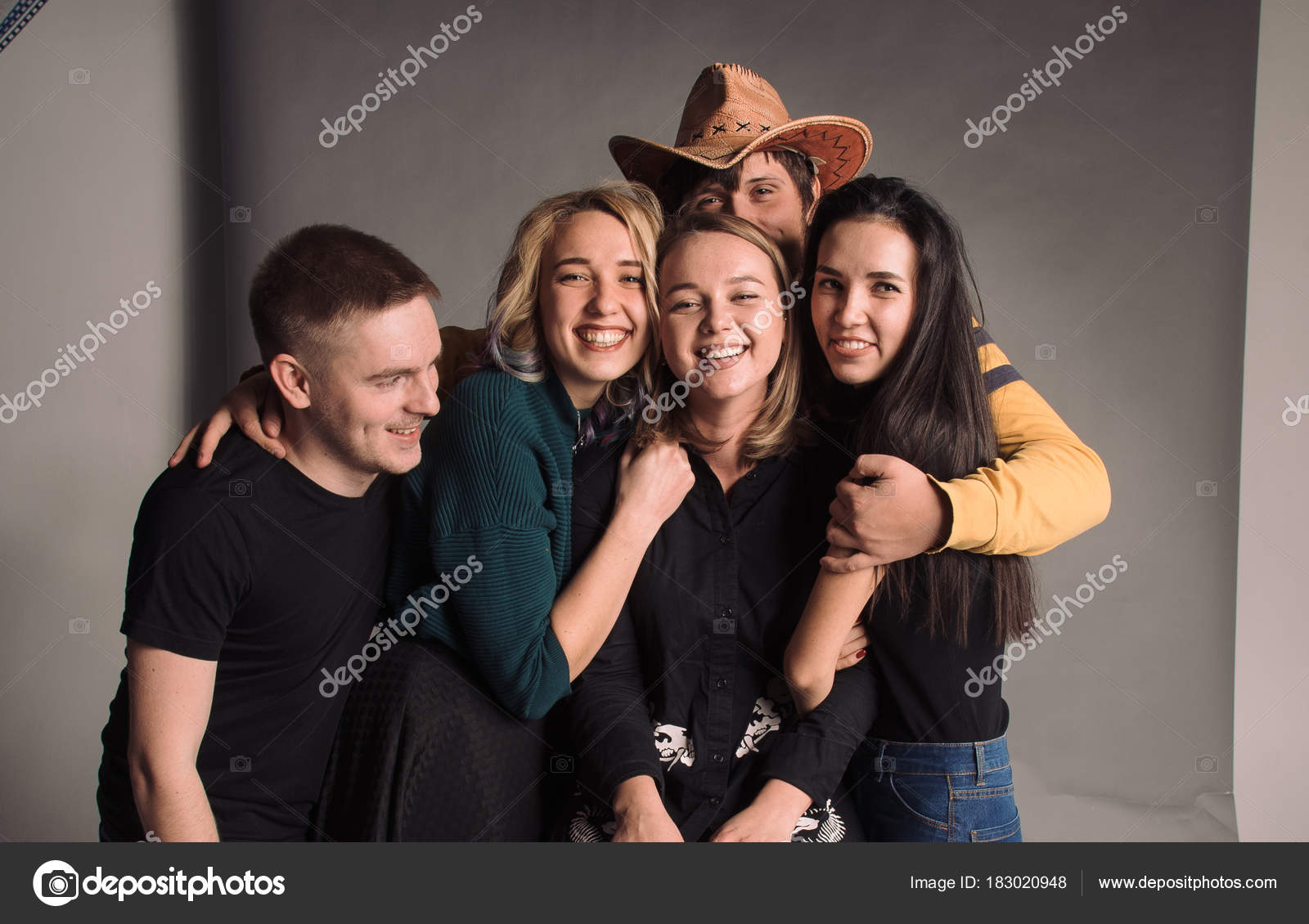 Five cool young friends standing together, hugging, laughing and ...