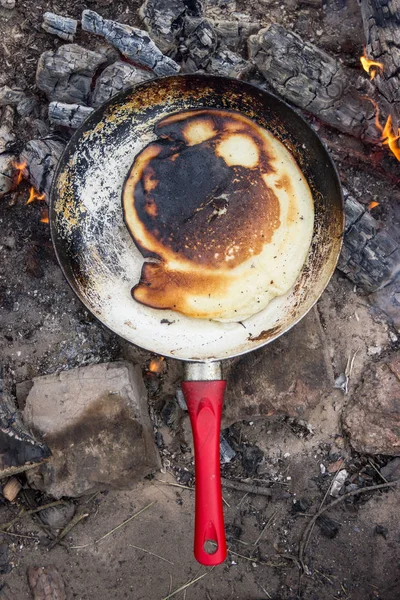 Pancake cooked on a fire in a frying pan with a red pen. - Stock Image ...